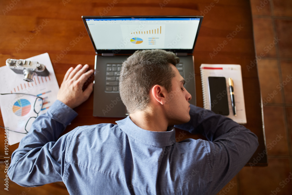 Top view of tired exhausted businessman sleeping on laptop keyboard at ...