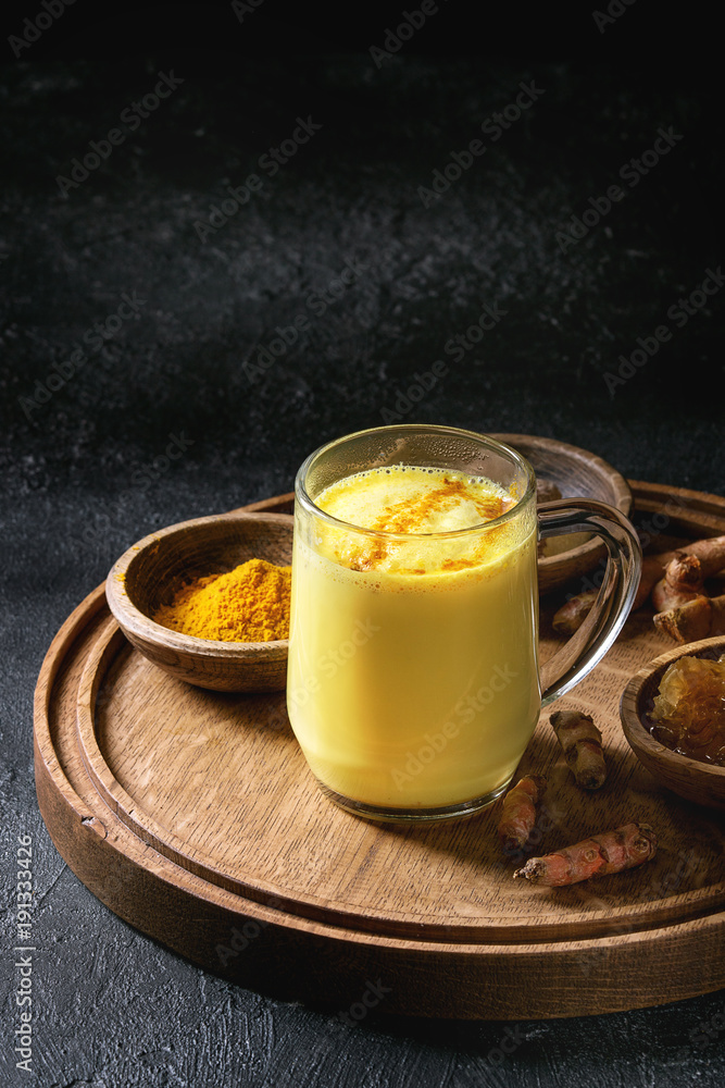 Cup of ayurvedic drink golden milk turmeric latte with curcuma powder ...