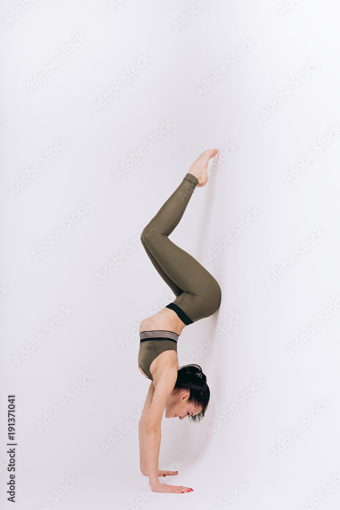 Gymnast girl performs stretching exercises on the white background ...