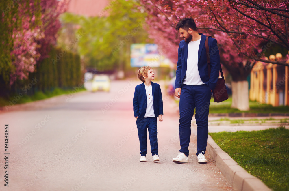 happy father and son walking together along blooming spring street ...