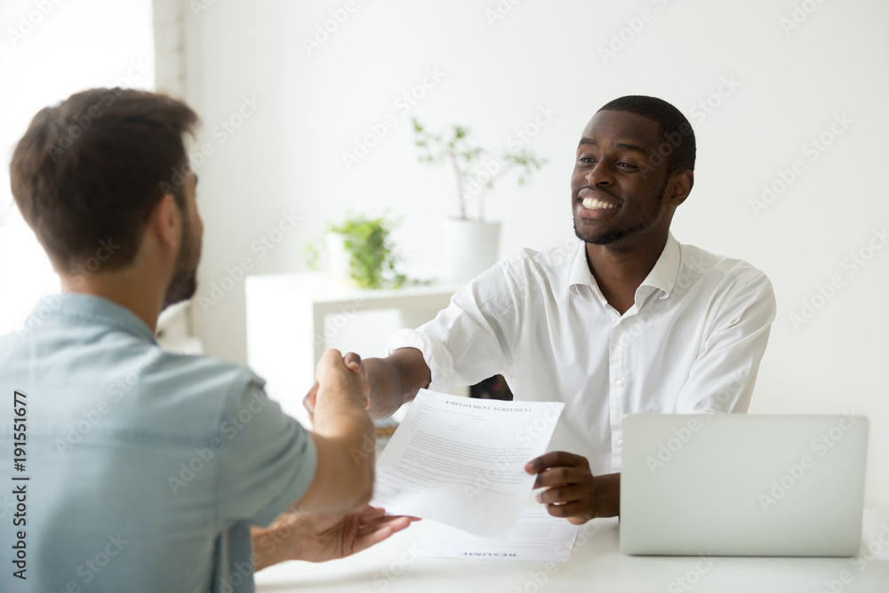 Friendly african american employer handshaking congratulating new hire ...
