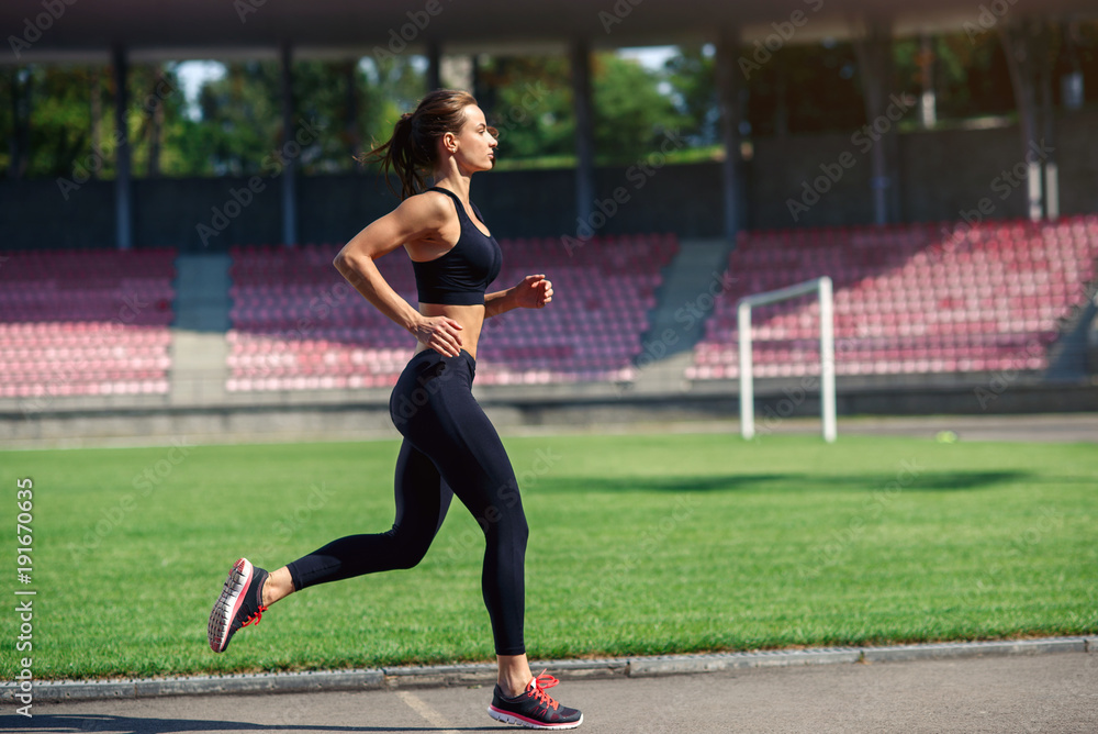 Young fitness woman running on a stadium track. Athlete girl doing ...