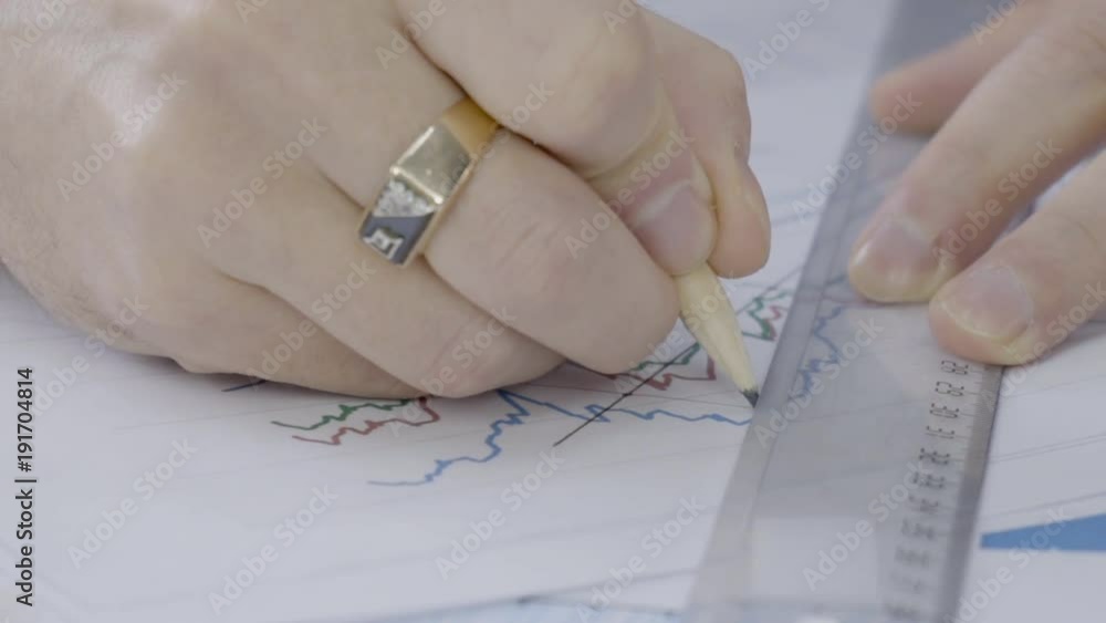 Close-up of a man drawing a line on a ruler on the chart. Man's hand in ...