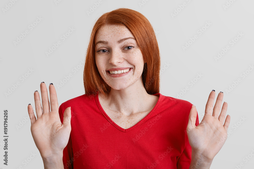 Pleasant looking red haired female in red clothes, shows palms ...