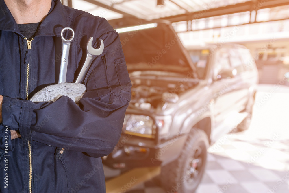 Car repairman wearing a dark blue uniform standing and holding a wrench ...