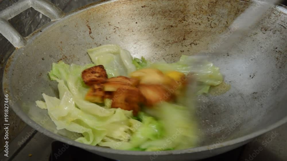 Iceberg lettuce and fried tofu cooking in iron pan on fire gas stove ...