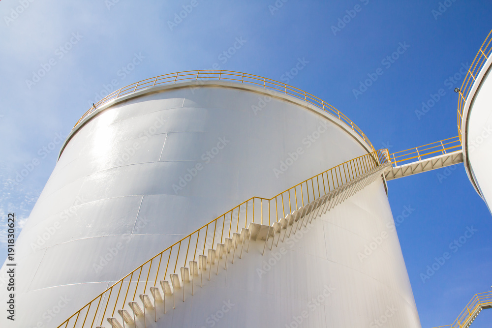 white storage tanks, fuel steel silos with yellow stair ladder against ...