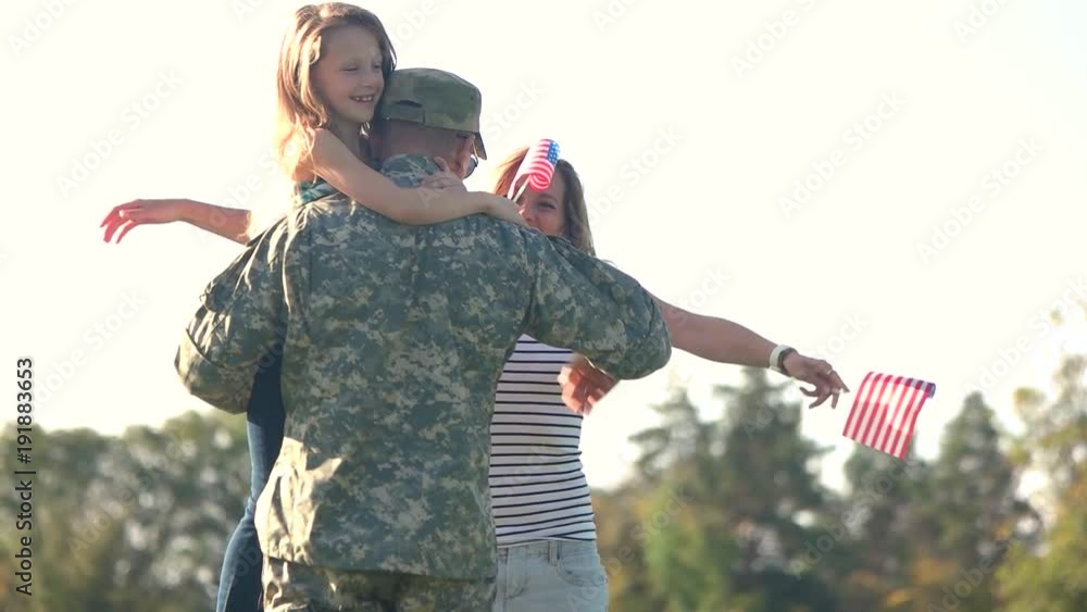 Soldier reunited with his family on a sunny day in the park. Happy ...