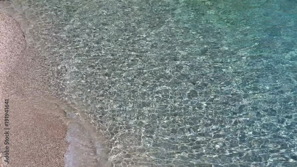 Paradise sea ripple water surface with sunlight glow and pebble bottom ...