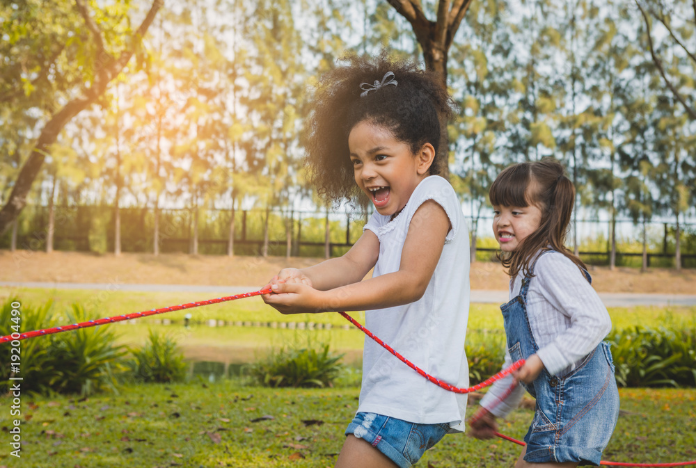 Happy kids playing rope tug of war in park Stock Photo | Adobe Stock