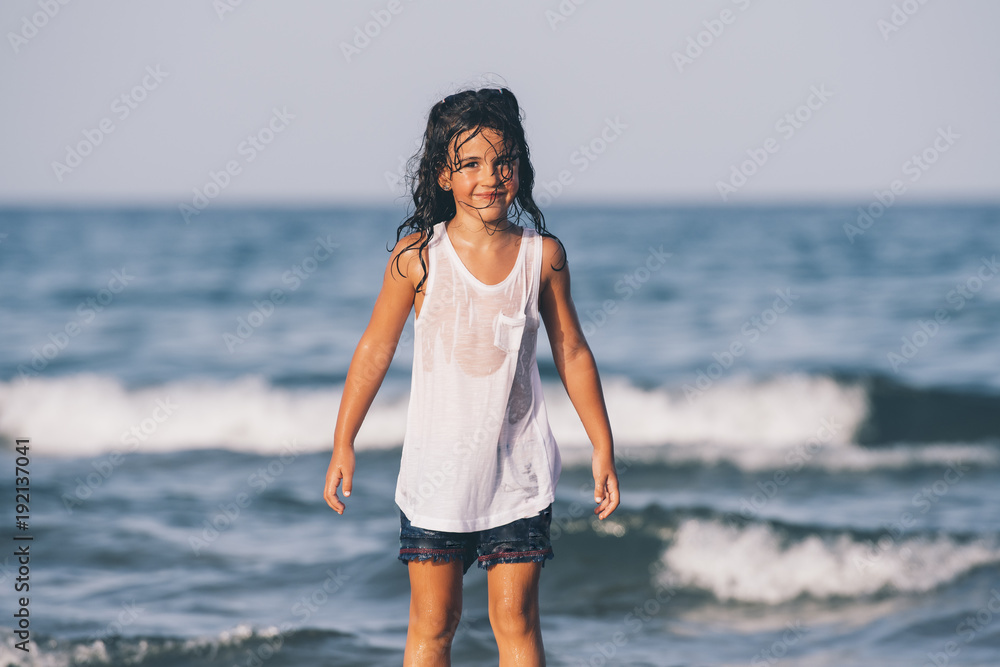 Little happy girl playing on the beach. Stock Photo | Adobe Stock