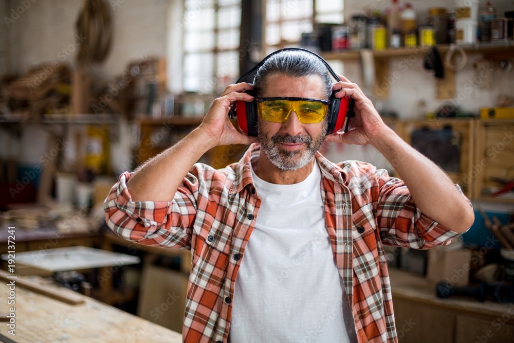 Portrait of carpenter holding ear muff Stock Photo | Adobe Stock