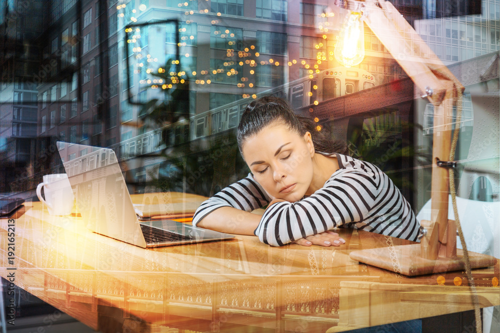 Short nap. Calm tired young woman sitting at the table with her eyes ...