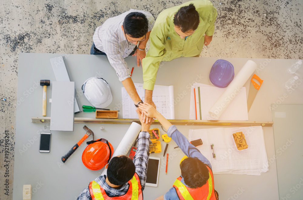 top view of group of engineer, technician and architect joining hands ...