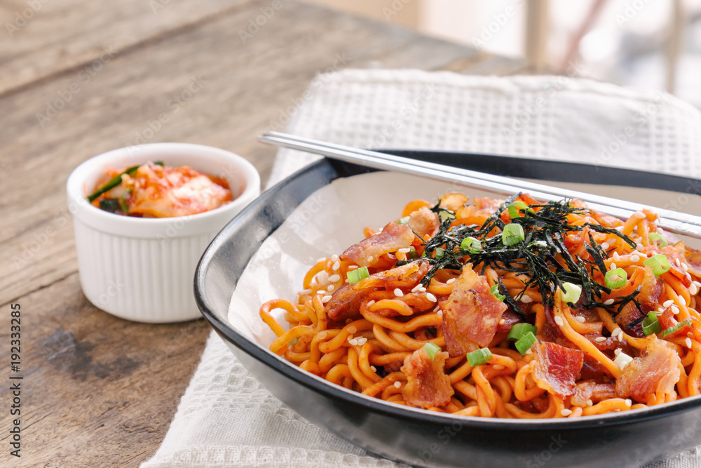 Korean hot and spicy instant noodle in blac bowl topped with bacon ...