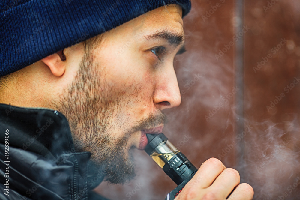 Vape man. Portrait of a handsome young white guy vaping an electronic ...