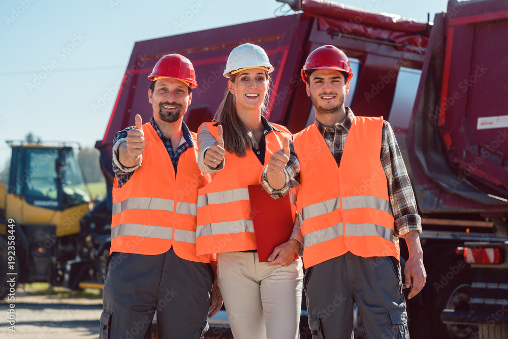 Colleagues in a freight forwarding company giving thumbs up in front of ...