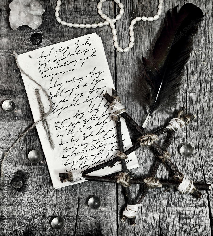 Paper manuscript with hand written text, pentagram and quill on planks ...