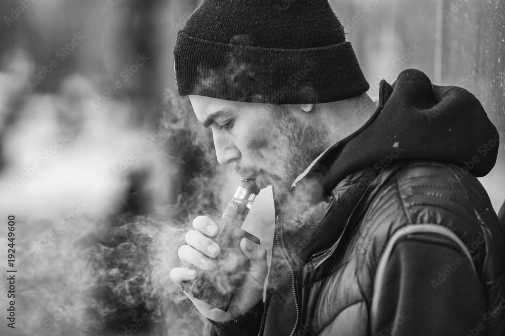 Vape man. Portrait of a handsome young white guy in black waistcoat and ...