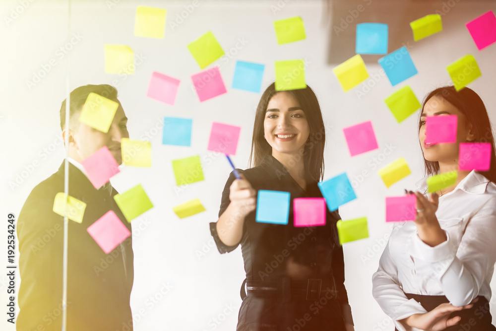 Young male and female coworkers writing remaining notes for colleagues ...