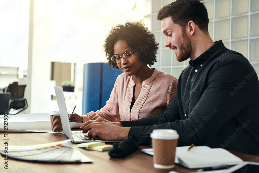 Diverse colleagues using a laptop together at an office desk Stock ...