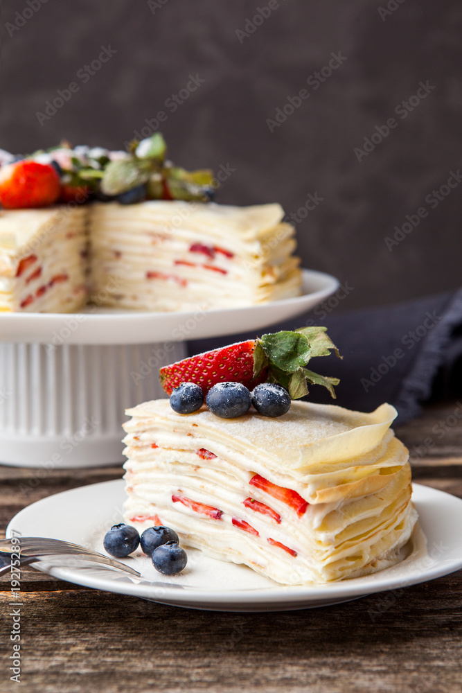 Crepe cake bakery piece with strawberry and vanilla sauce on wood table ...
