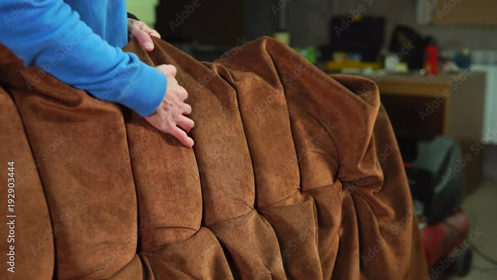 Skilled workman is making a luxury sofa. He is wrapping a base by ...