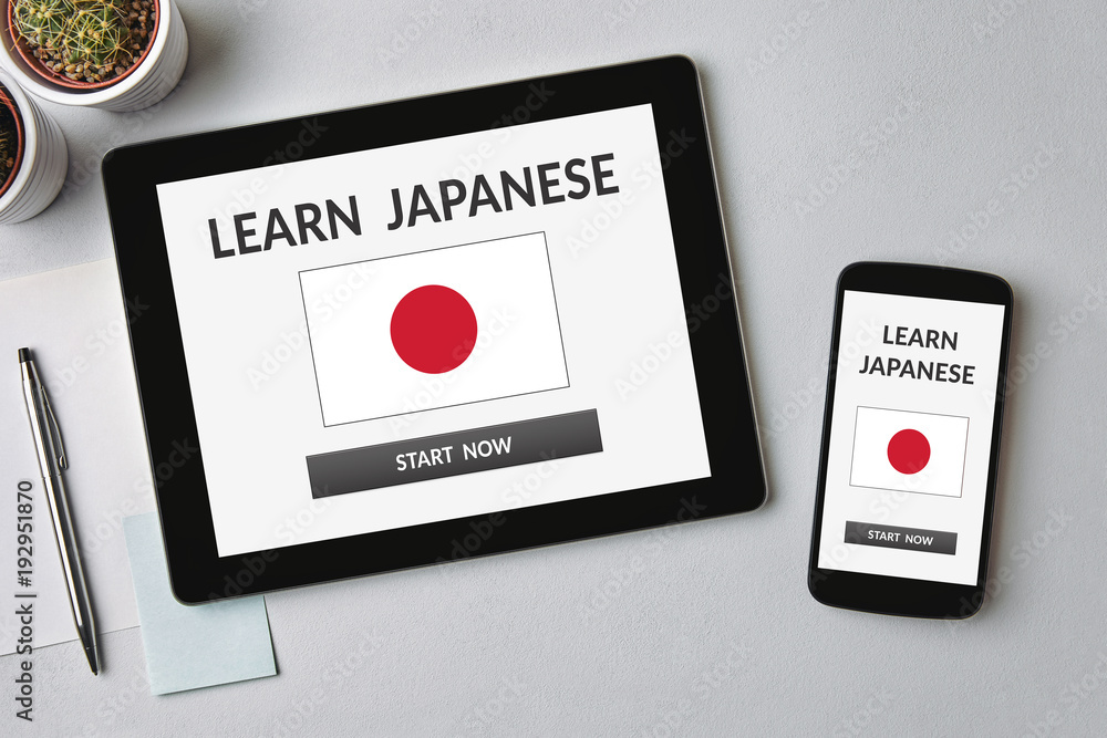 Learn Japanese concept on tablet and smartphone screen over gray table ...