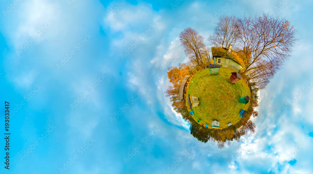 Green little planet with trees and apiary, white clouds and soft blue ...