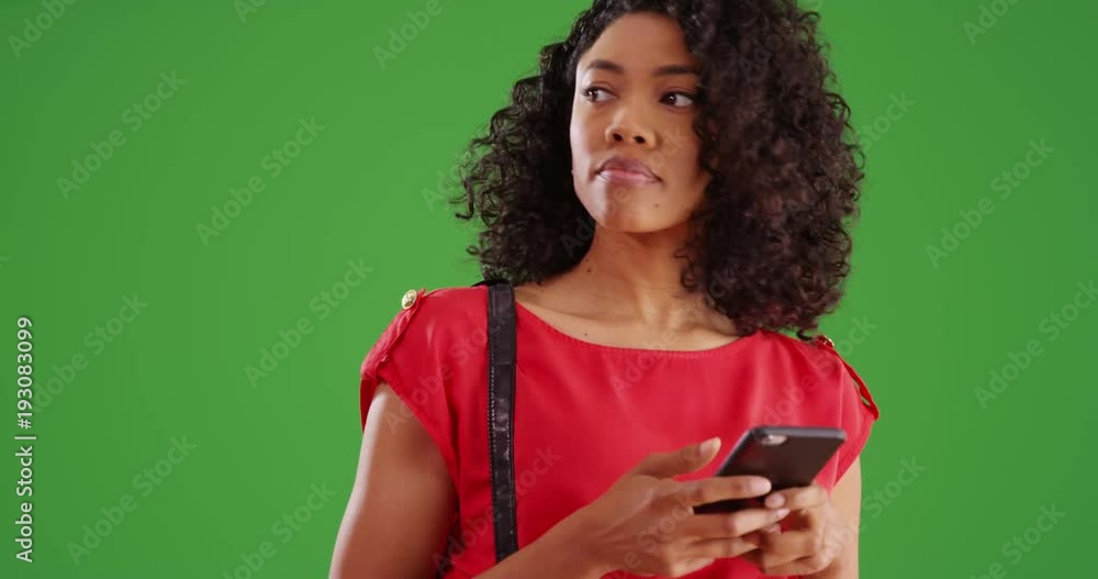 Pretty Black woman texting with cell phone and smiling on greenscreen ...