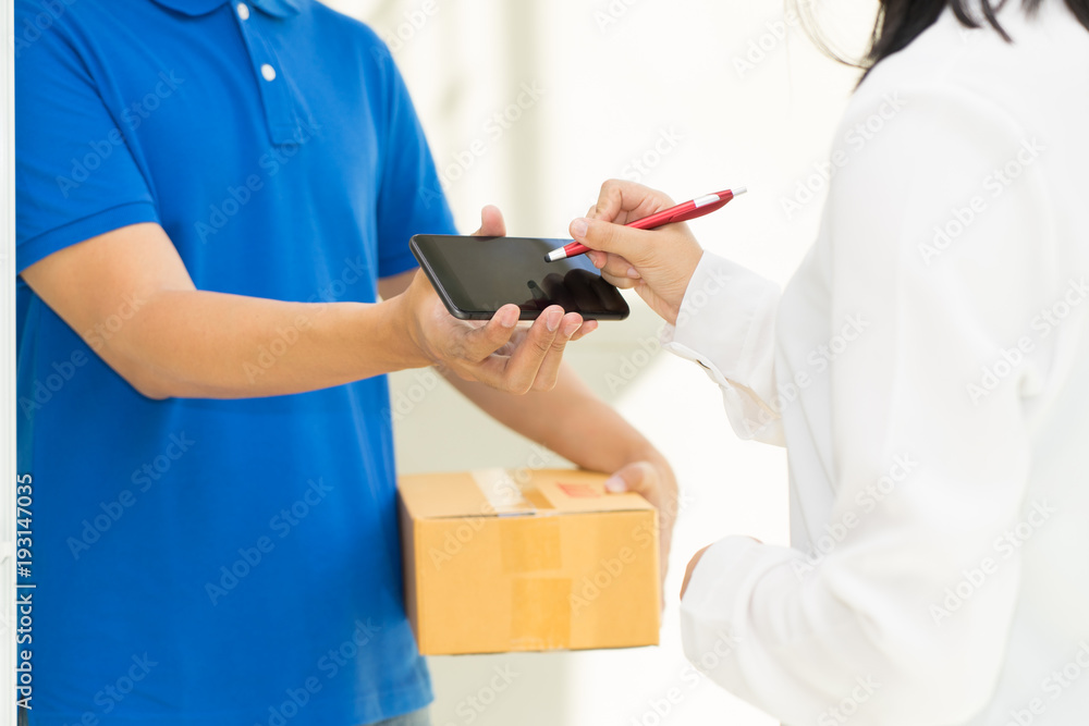 Delivery man pointing on smartphone and woman receiving package and ...