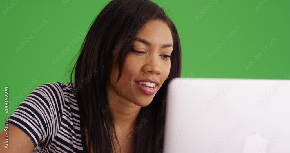 Close up over the screen view of black woman working on laptop computer ...