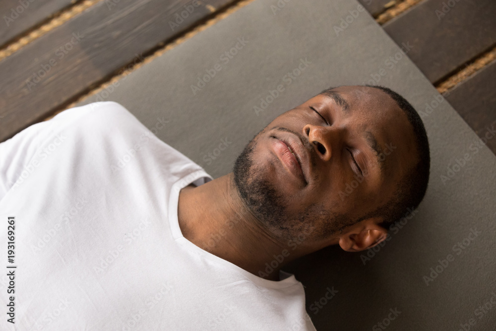 Foto Stock Photo Of Young Black Man Lying In Dead Body Exercise Or Corpse Pose With His Eyes foto-stock-photo-of-young-black-man-lying-in-dead-body-exercise-or-corpse-pose-with-his-eyes