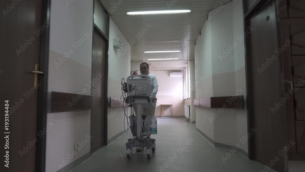 Female medical technician pushing portable ultrasound device and ...