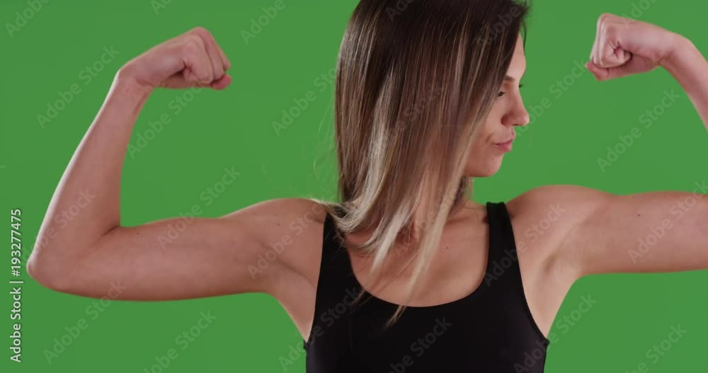 Athletic and fit young millennial woman flexing biceps and kissing her ...