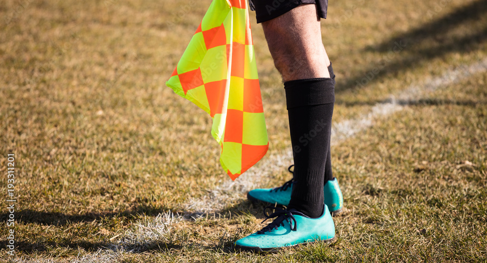Soccer referee assistant stands at sideline with flag at hands. Blur ...