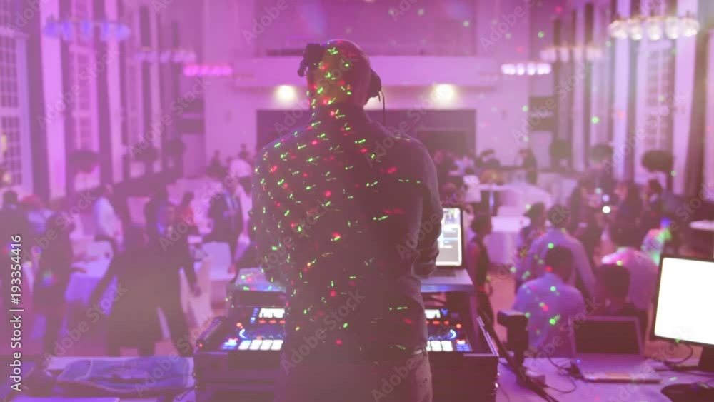 Unrecognizable Rear view of DJ mixing dancing in front his turntables ...