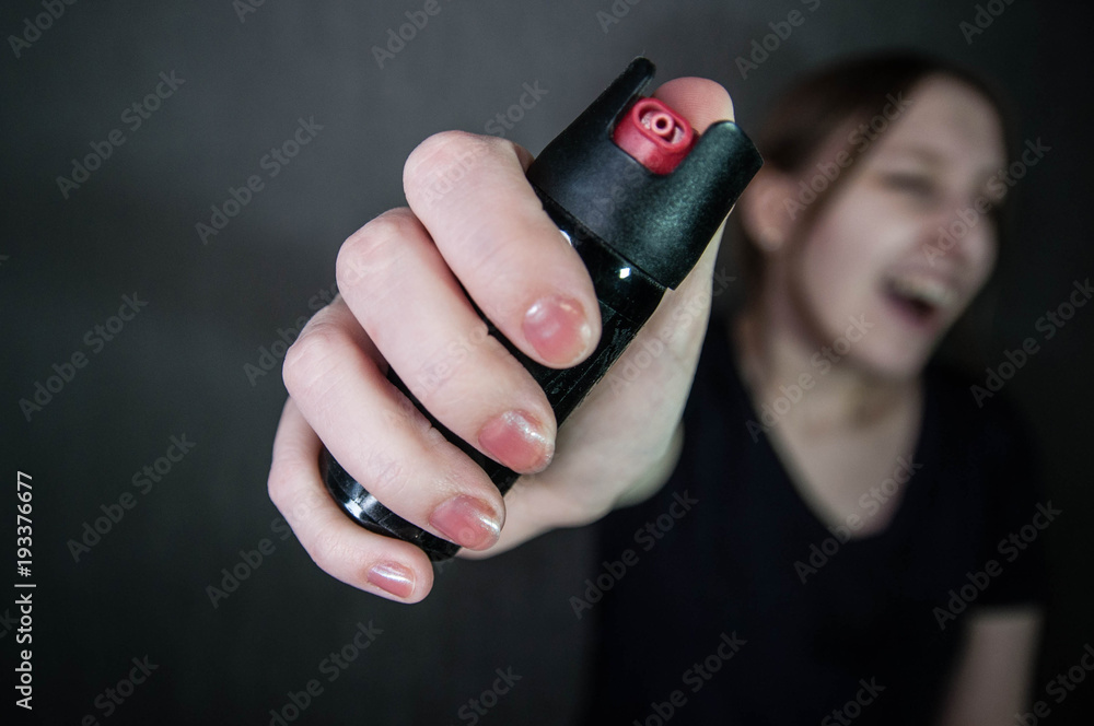 Self-defense concept: a young girl defends herself with a gas bottle ...