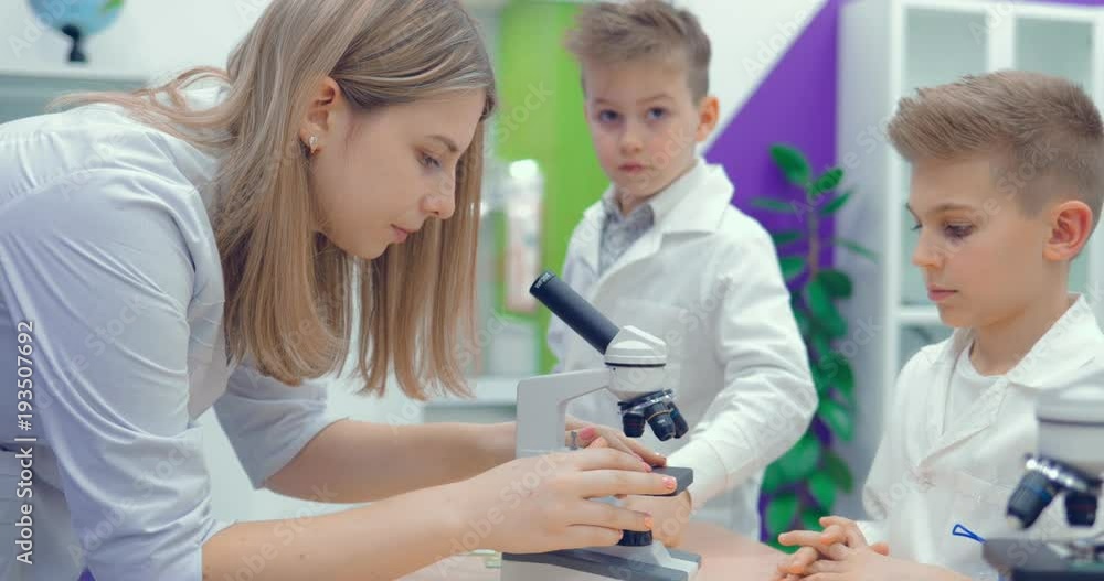 Teacher helps students create a laboratory microscope for work Stock ...