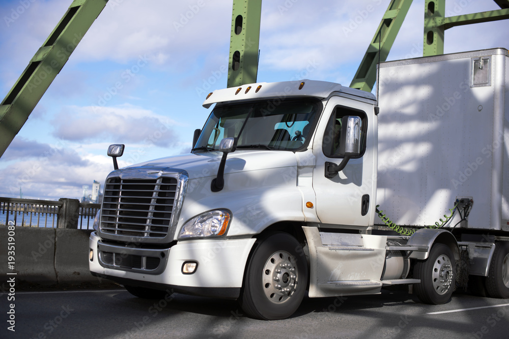 Big rig day cab semi truck with dry van semi trailer running on the ...