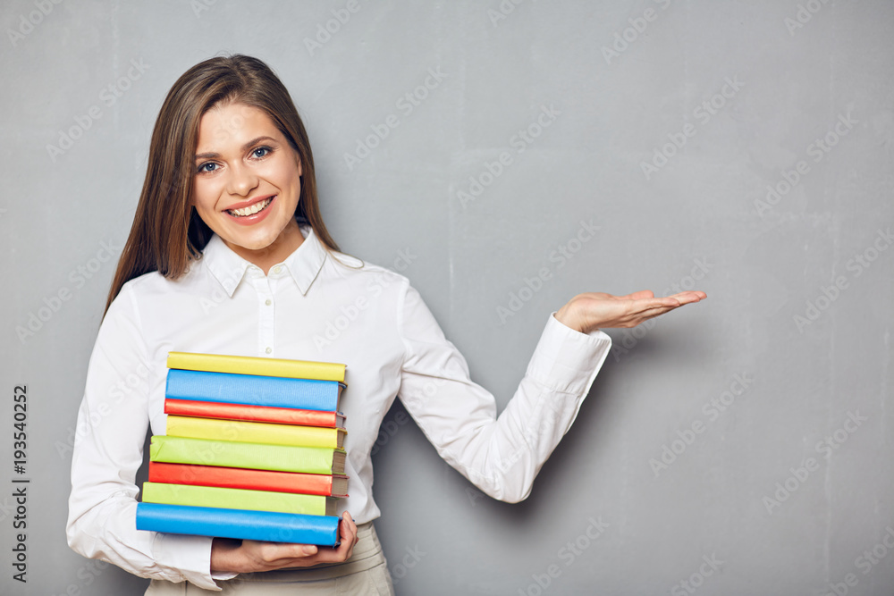 Foto Stock Smiling student girl holding books and presenting empty hand ...