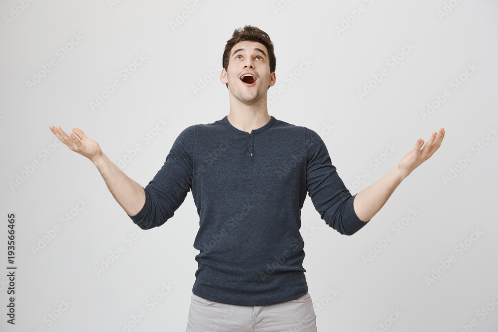Portrait of fascinated excited young guy looking up with happy ...