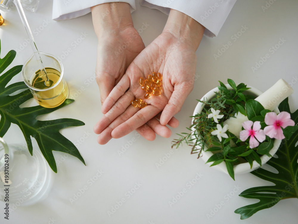 scientist or doctor making herbal medicine with herb leaves , capsule ...