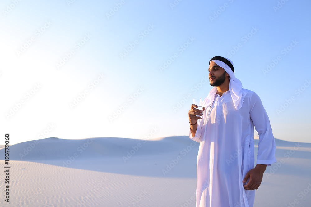 Stately Arab young man quenches thirst with glass of cool water and ...
