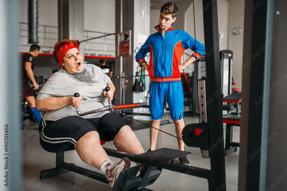 Instructor forces fat woman to work in gym Stock Photo | Adobe Stock