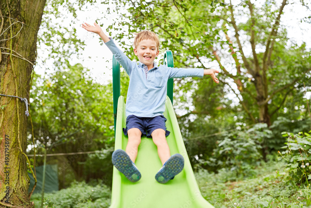 Fröhlicher Junge rutscht die Rutsche herunter Stock Photo | Adobe Stock