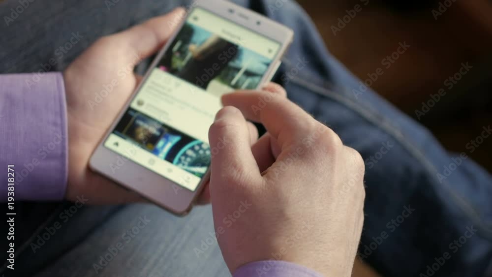Man using his smartphone with to scroll an account feed, scrolling news, tapping on screen. The ...