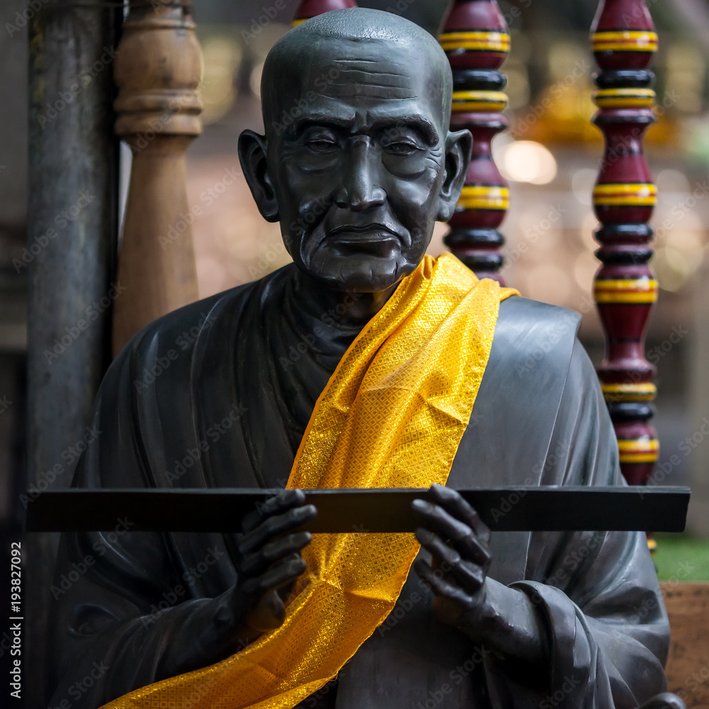 Bronze sculpture of the old Buddhist monk of Asian appearance reading ...