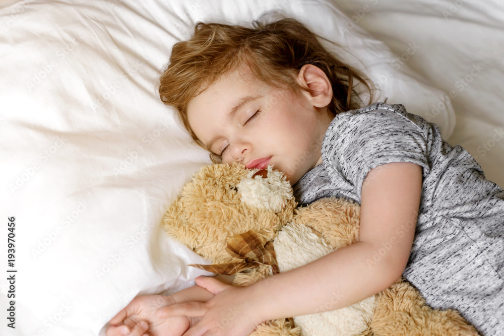 Beautiful baby girl sleeping in my own bed at home with a favorite toy ...