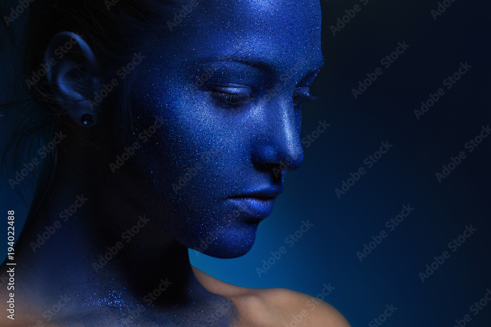 beautiful girl face painted with blue paint with glitter. blue powder ...